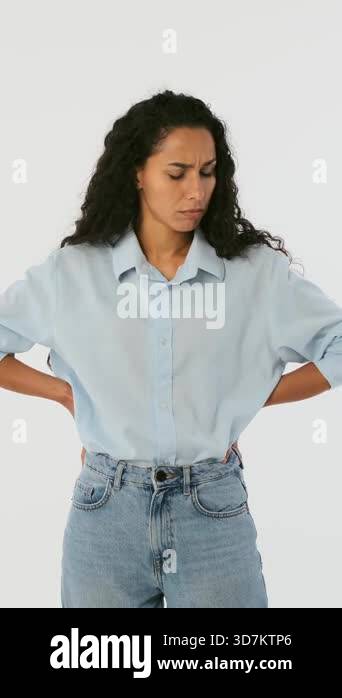 Bored young woman with curly hair waiting and looking impatient. Dissatisfied female thinking ...