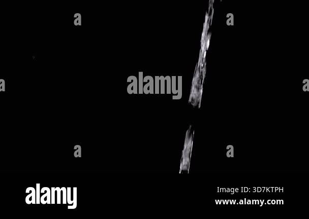 A pulsating stream of water, with splashes, pours on a black background ...