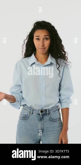Confused young woman shrugging shoulders and making facepalm gesture ...
