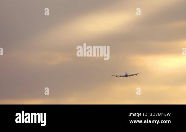 Wide-body four-engine aircraft ascending into the colorful sky during ...