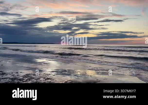 A calm and tranquil beach landscape during sunset, featuring soft waves ...