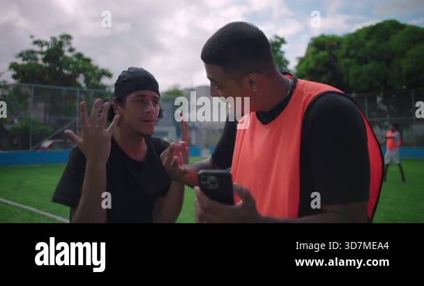 Two Hispanic men standing on soccer field, one showing shocking content ...