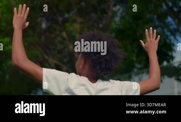 Young African American man raising hands toward the sky from behind ...