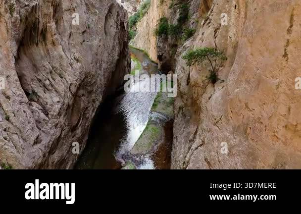 The sunlight glistening on a stream winding through a steep and narrow ...