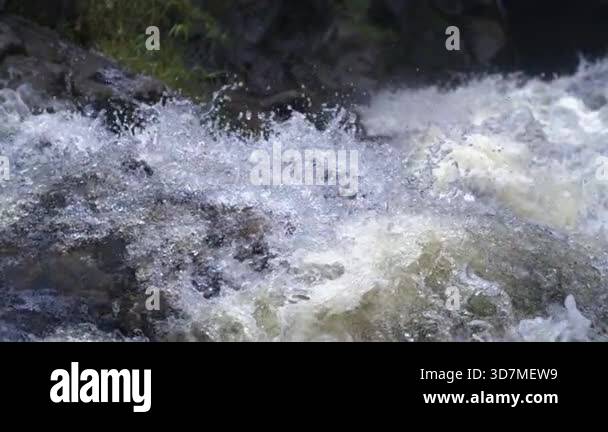 Splashing water droplets bursting from rocky waterfall edge in Ultra ...