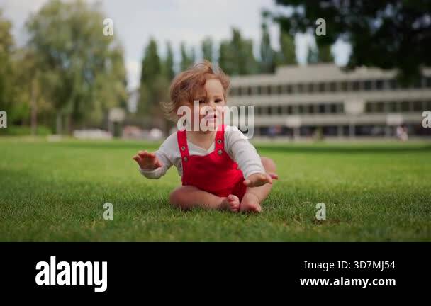 Toddler crawling on green grass toward camera in open park, showing ...