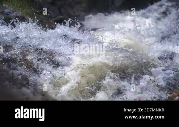 Foamy waterfall water rushing over rocks with strong flow in Ultra slow ...