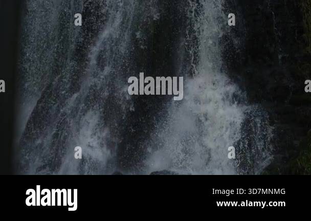 Falling water crashing into rocks at base of waterfall, filmed in ultra ...