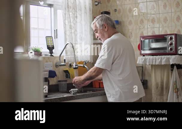 Elderly Man Washing Dishes In Kitchen As Part Of Daily Household Chores ...