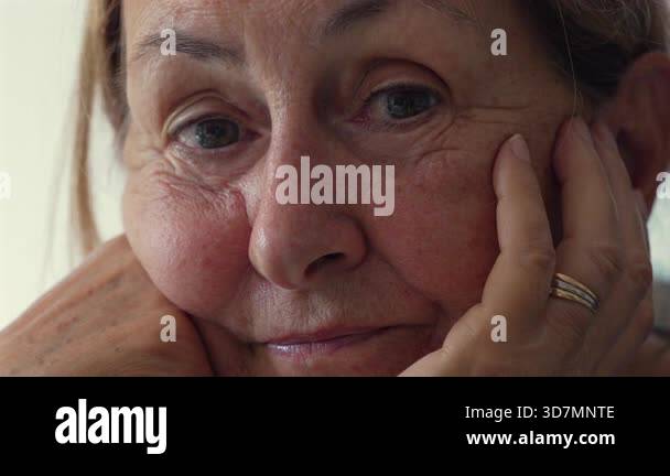 Elderly woman resting her face on hand with calm and reflective ...
