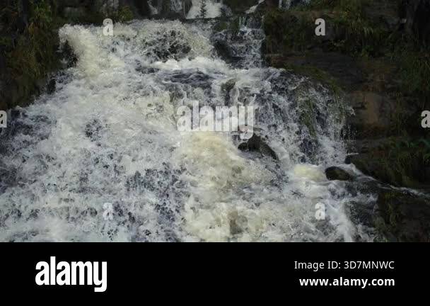 Low angle shot of rushing white water descending over layered rocks of ...