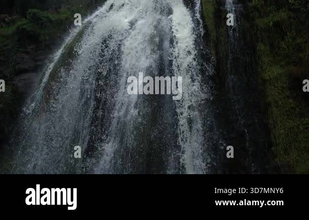 Tall waterfall dropping over dark rock cliff face in Ultra slow motion ...