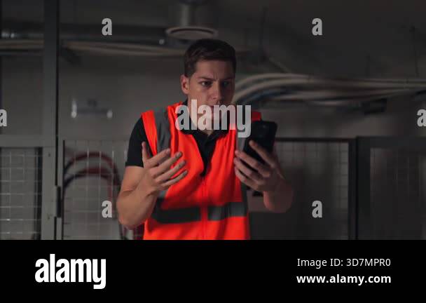 Worker wearing safety vest displays concern and confusion while viewing ...