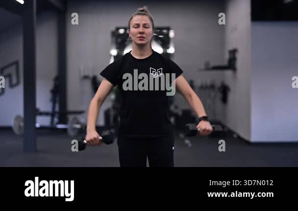 A woman demonstrates upper body strength exercises using dumbbells in a ...