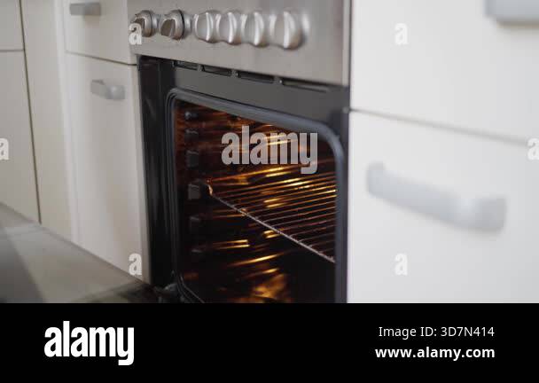 pizza in oven, hands sliding tray into heated home oven for baking ...