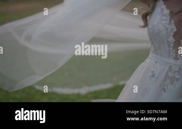 Slow motion video of a bride standing outdoors as the wind gently lifts ...