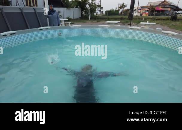Little girl swimming watched by her grandmother from behind Stock Video ...