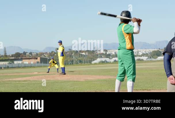 Pitcher delivering pitch, man in green uniform swinging bat and ...