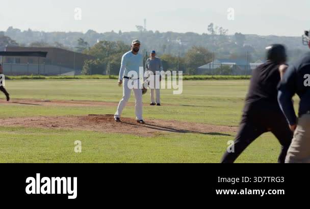 Umpire signaling ready, senior male pitcher on mound winding up ...