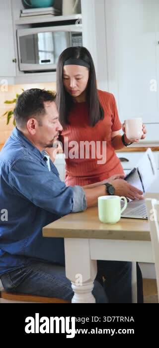 Vertical video: Noticing stress, Asian couple reviewing documents on ...