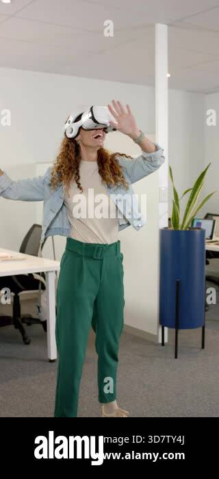 Vertical video: Entering office wearing VR headset, woman is grabbing ...