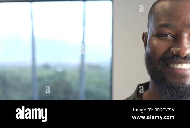 Mid adult African American man standing at window facing camera smiling ...