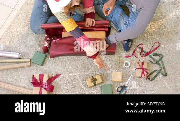 After unfurling red paper at home, couple wrapping gift for holiday ...