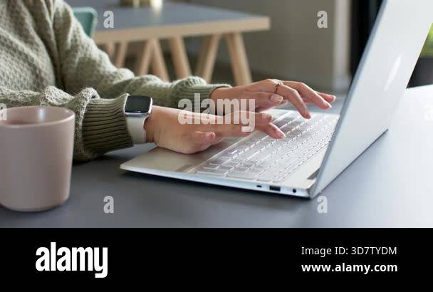 Typist settling at desk beside laptop is pressing keys while adjusting ...