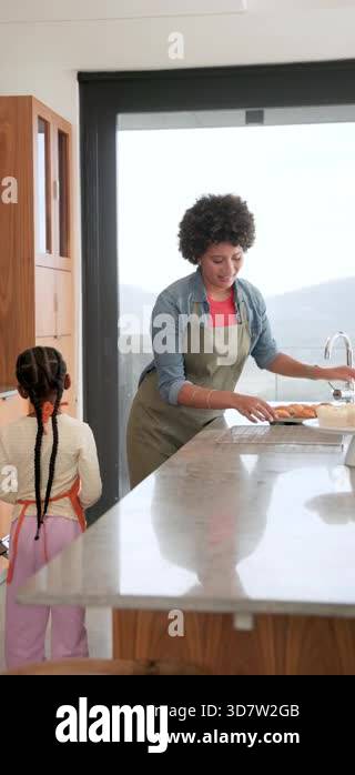 Vertical video: Opening oven mother guiding African-American girl ...