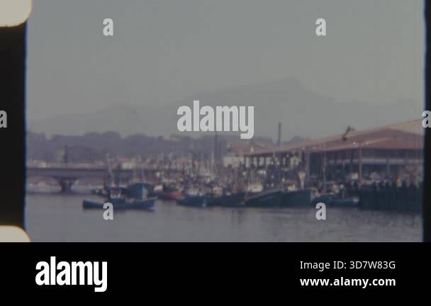 Several boats rest at a harbor on 8mm film, their stillness contrasted ...