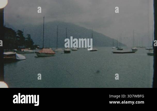 Retro 8mm film capturing a tranquil lakeside scene with sailboats ...