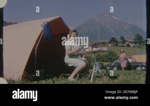 A couple enjoys a picnic outdoors near a tent, captured on 8mm film ...