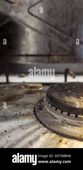 close-up gas burner ignites blue flame, grimy oven interior with ...
