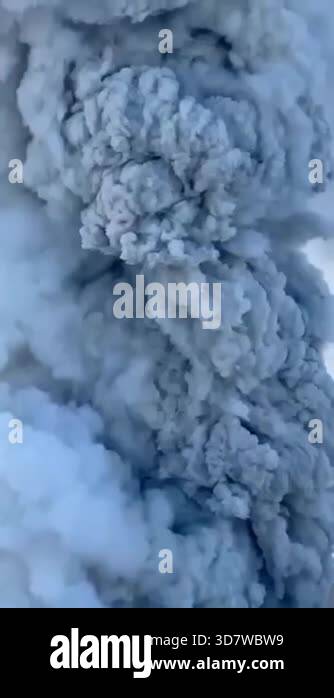 A massive, dense column of grey smoke rising vertically into the air ...