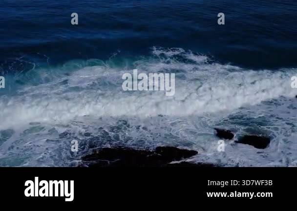 High-angle view of powerful deep blue ocean waves crashing against the ...