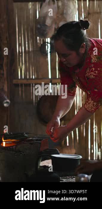 Southeast Asian couple preparing a meal together on a wood stove in ...