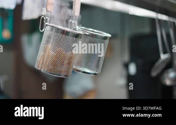 Hot pasta drained in a small wire mesh strainer in the kitchen of a ...