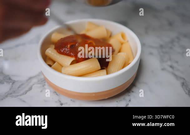 Professional cook pouring fresh tomato sauce and adding basil over ...
