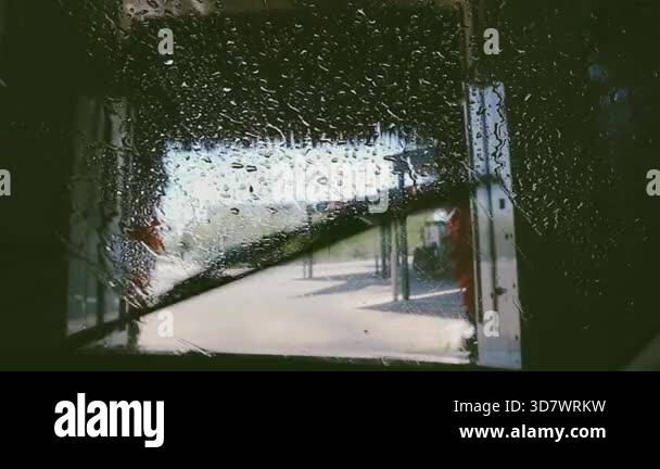 View from inside a car wash with water droplets on the windshield. The ...