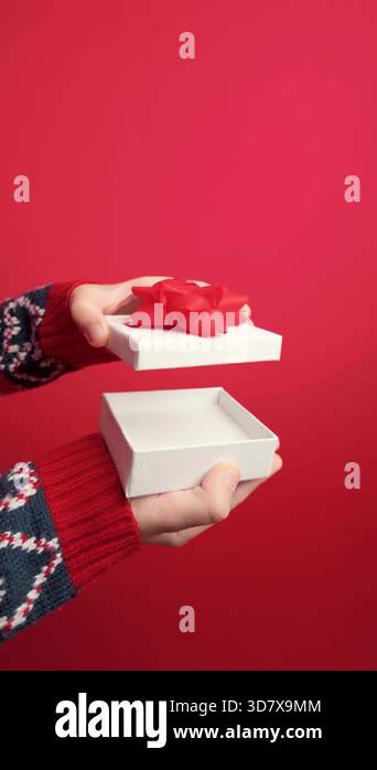 Vertical slow motion shot of a girl opening a small wrapped gift with ...