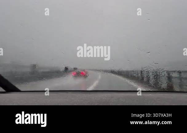 Driving on a highway during intense rain, a vehicle struggles with ...