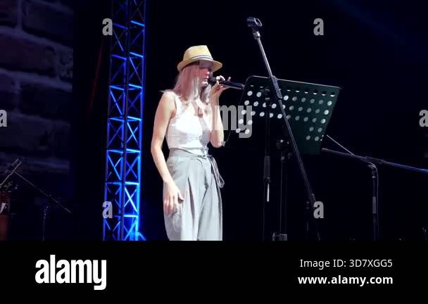 Young woman singing on stage at night during a live concert ...