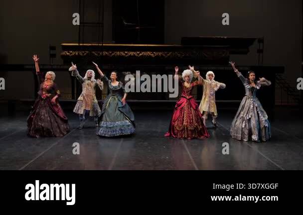 Actors in Baroque costumes perform a dance on stage. Luxurious dresses ...