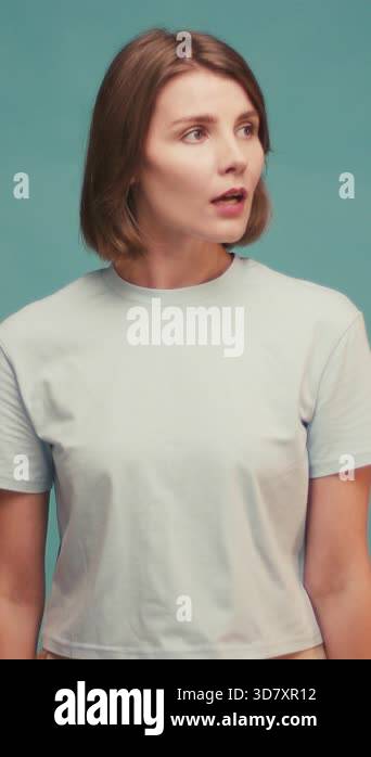 Beautiful hispanic woman holding finger on lips, blue studio backdrop ...