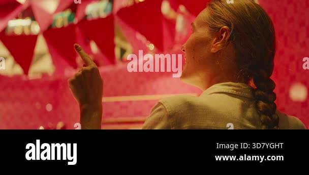 Woman smiling and pointing at something in a festive shop window ...