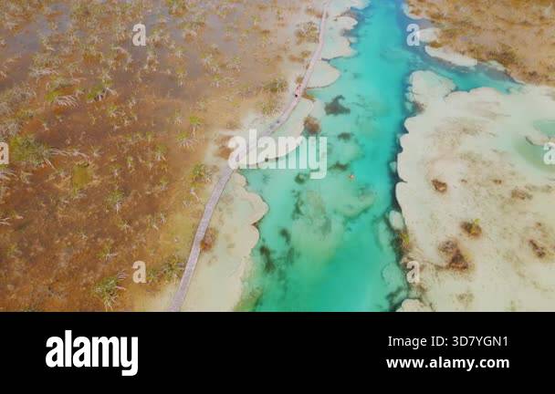 Wooden boardwalk over clear blue Bacalar canal with tourists floating ...