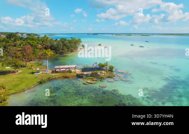 Bacalar Lagoon shore with piers and boats on shallow turquoise water in ...