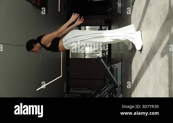 Woman performing a bending exercise in a modern gym. Vertical video ...