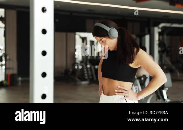 Woman adjusts her clothes and gets ready for her exercise routine in a ...