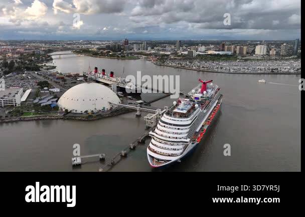 A high-angle drone shot that captures the Queen Mary, port cranes, the ...